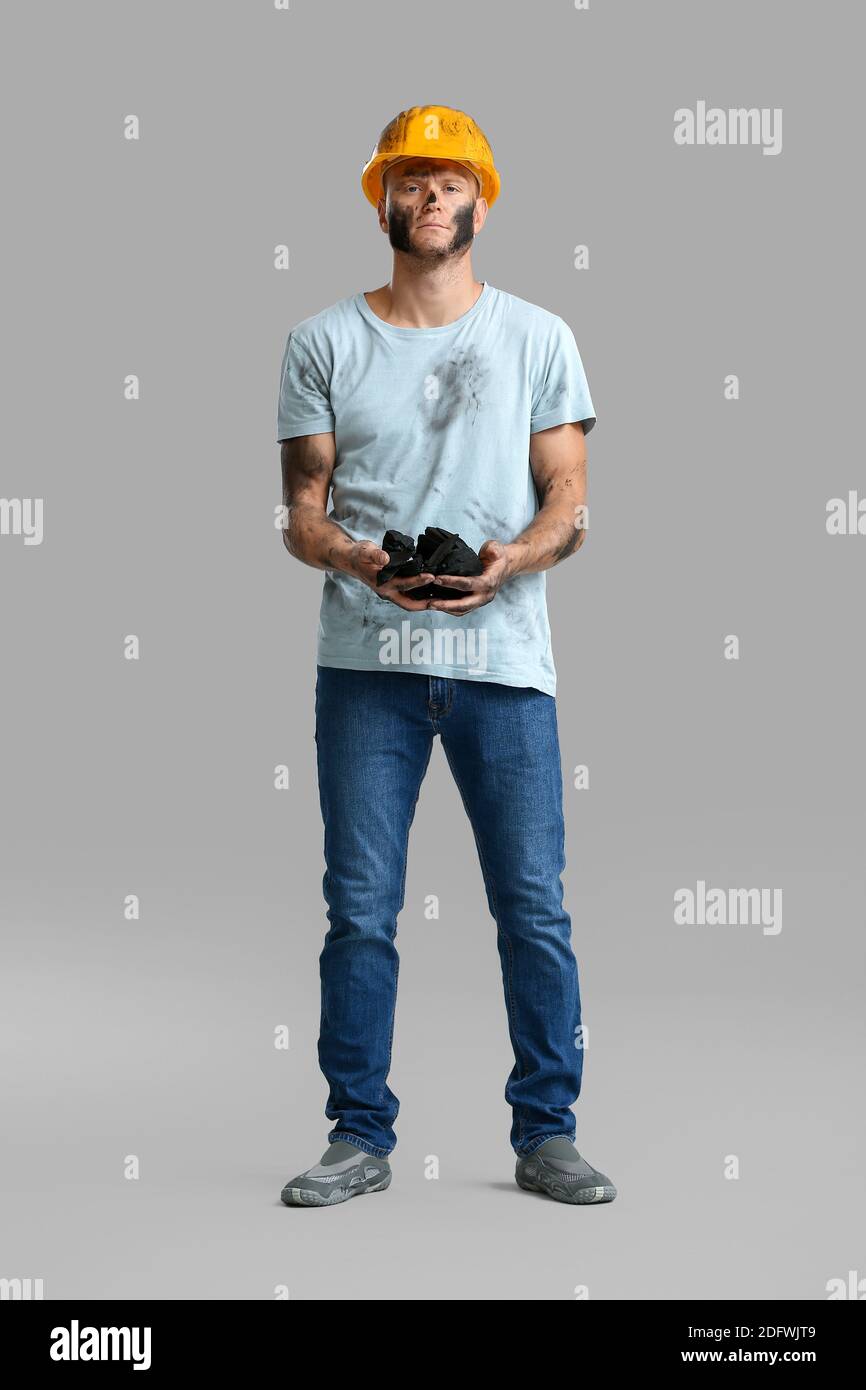 Miner man with coal on grey background Stock Photo - Alamy