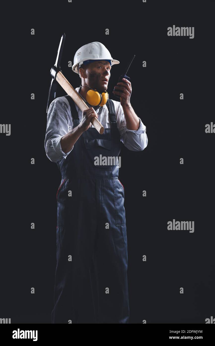 Miner man with pick axe and two-way radio on dark background Stock ...