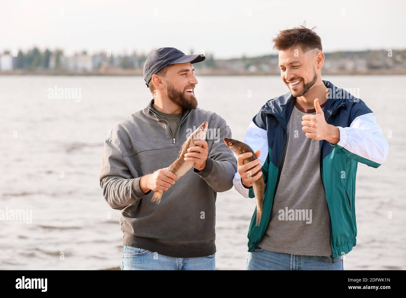 Happy young men fishing on river Stock Photo - Alamy