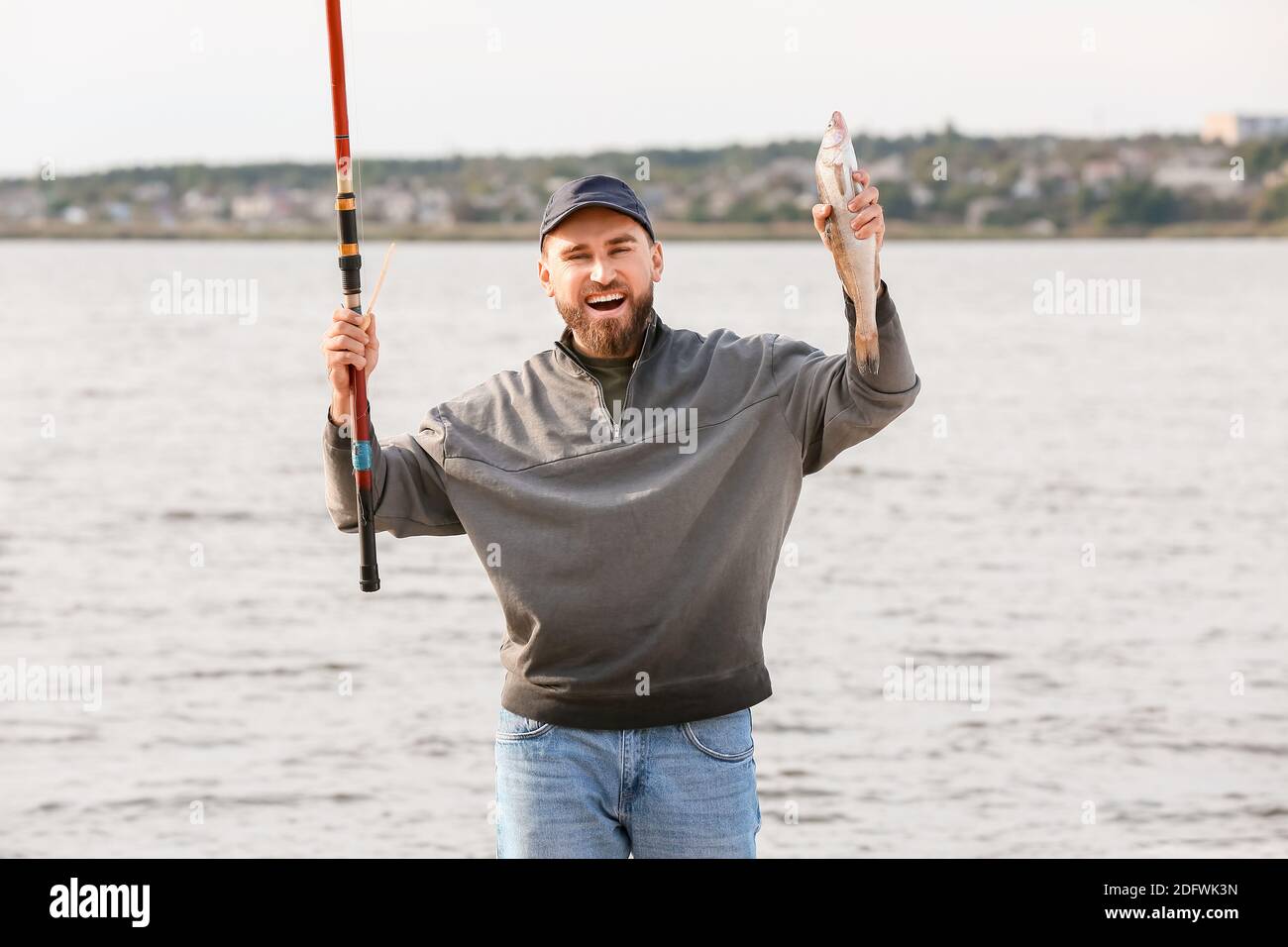 Happy young man fishing on river Stock Photo - Alamy
