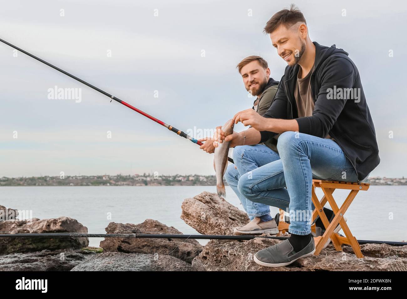Young men fishing on river Stock Photo - Alamy