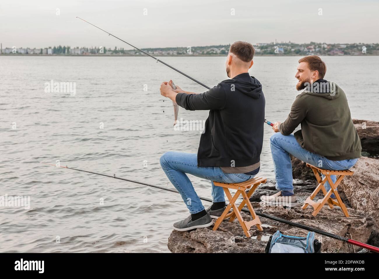 Young men fishing on river Stock Photo - Alamy