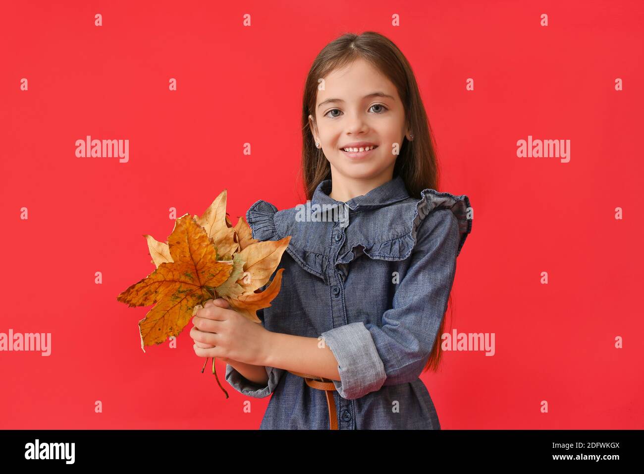 Cute little girl with autumn leaves on color background Stock Photo - Alamy
