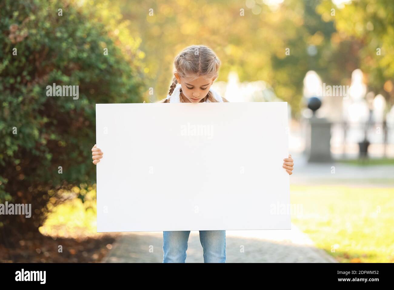 Cute little girl with blank poster outdoors Stock Photo - Alamy