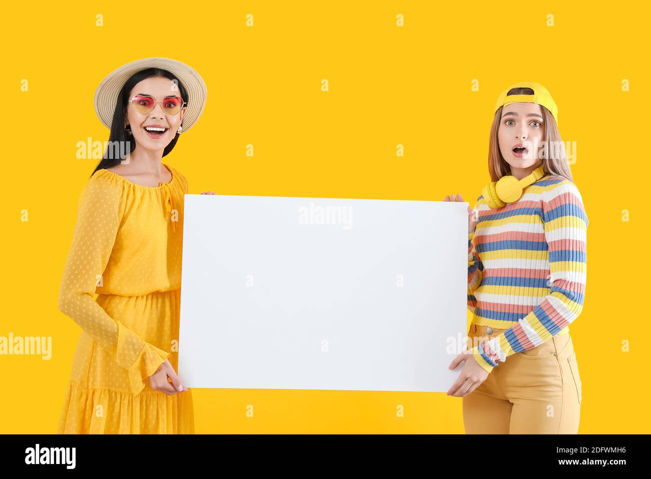 Beautiful young women with blank poster on color background Stock Photo ...