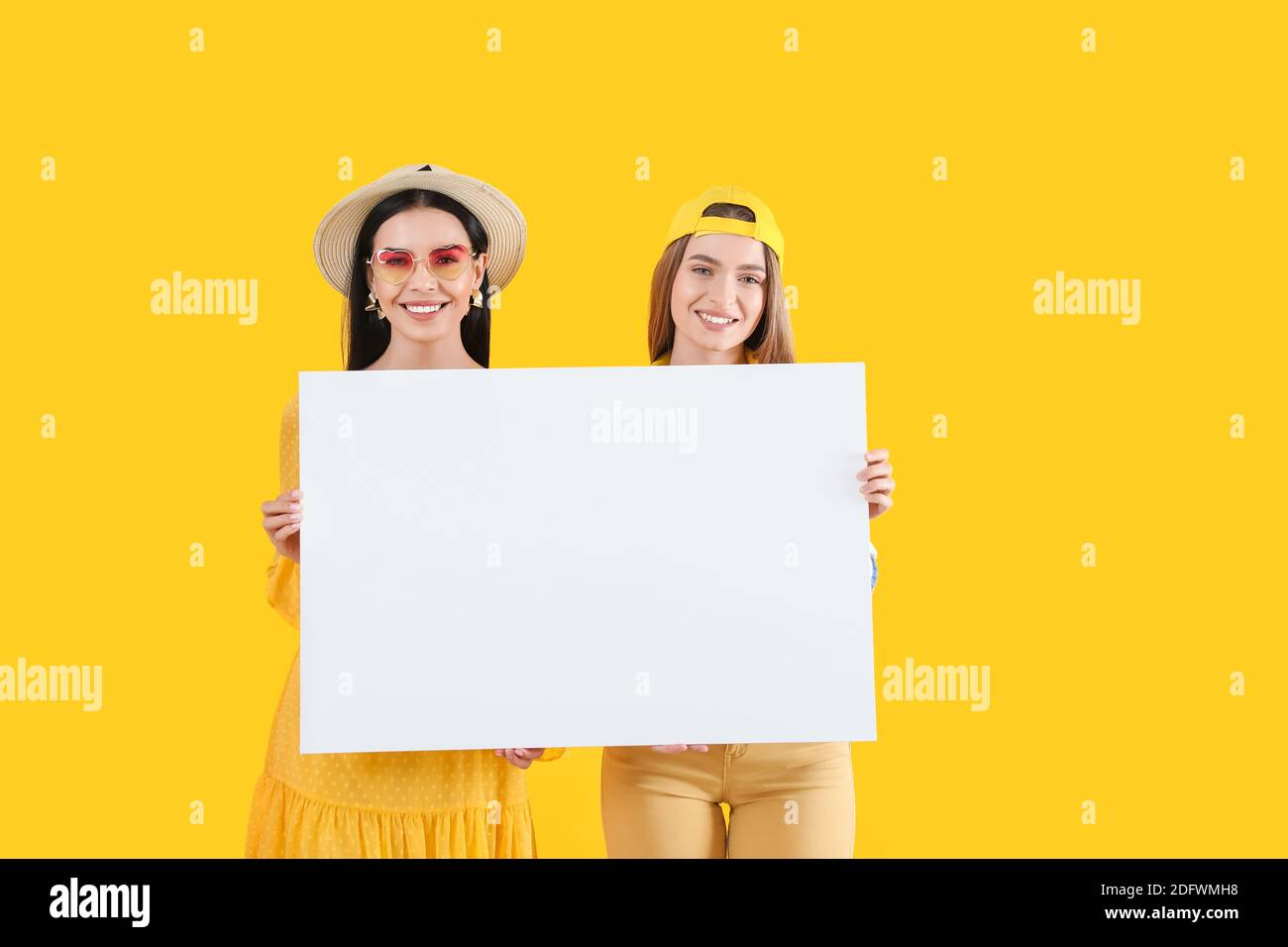 Beautiful young women with blank poster on color background Stock Photo ...