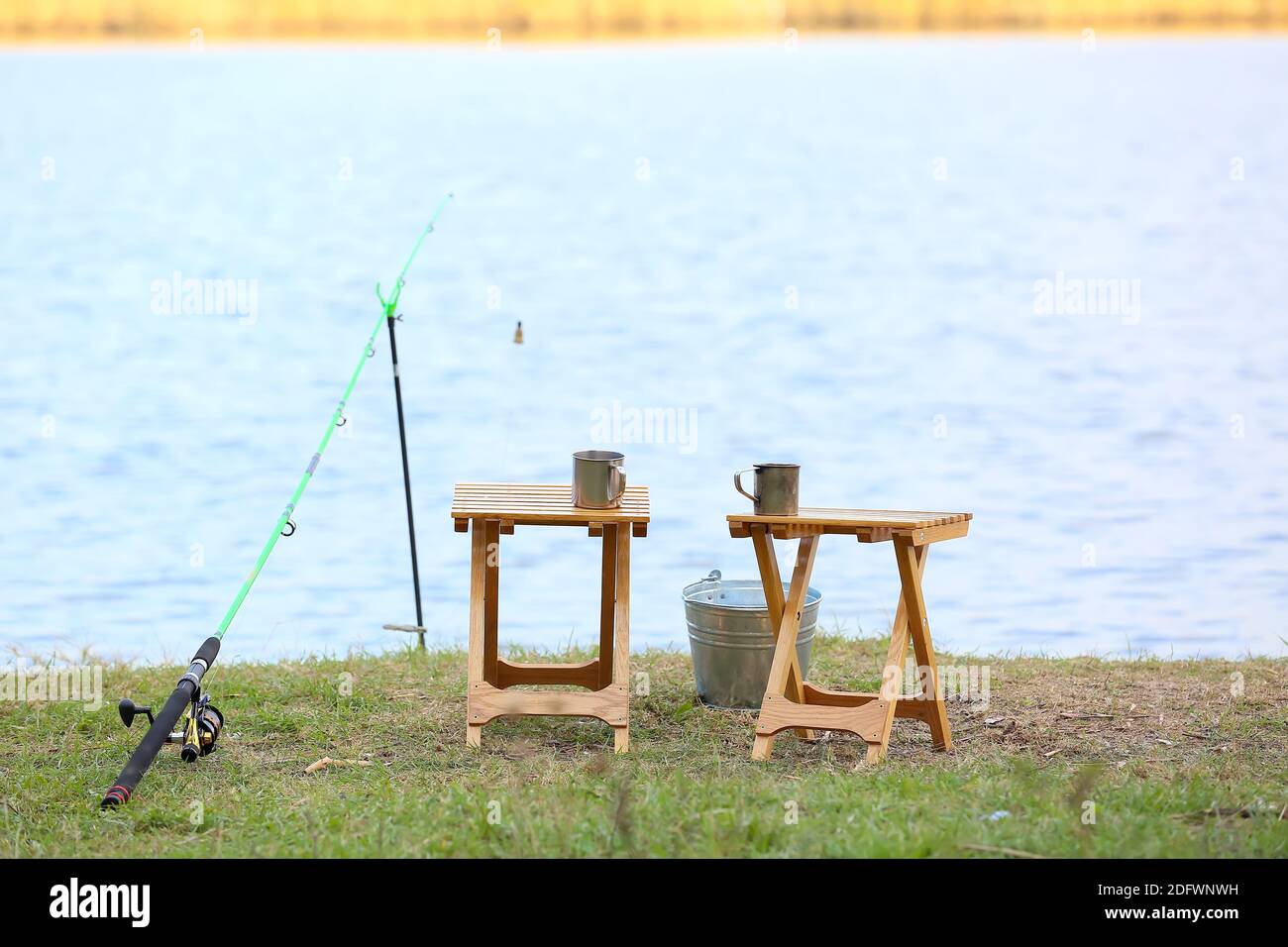 Fishing rod, bucket and stools on river bank Stock Photo - Alamy