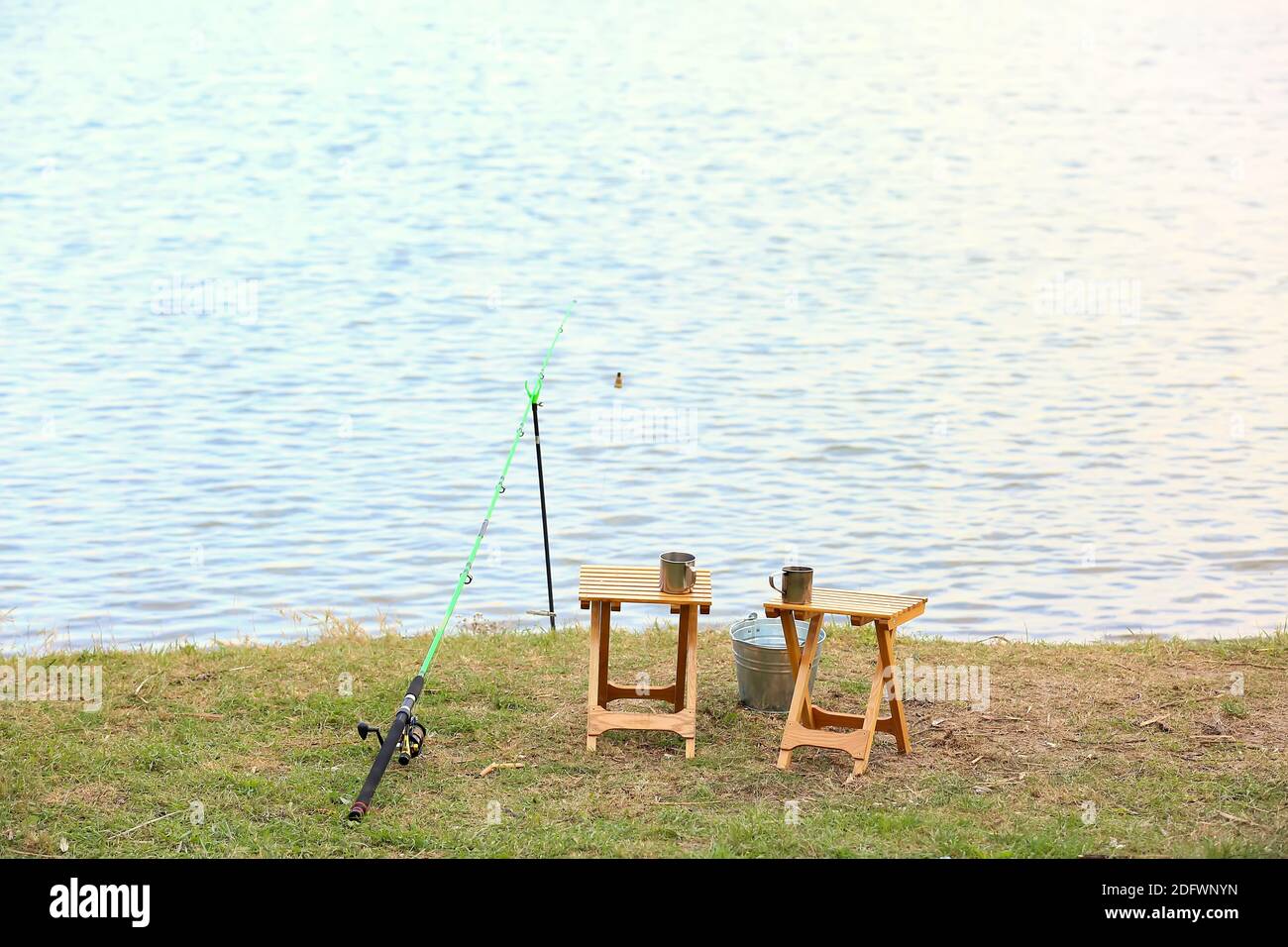 Fishing rod, bucket and stools on river bank Stock Photo - Alamy
