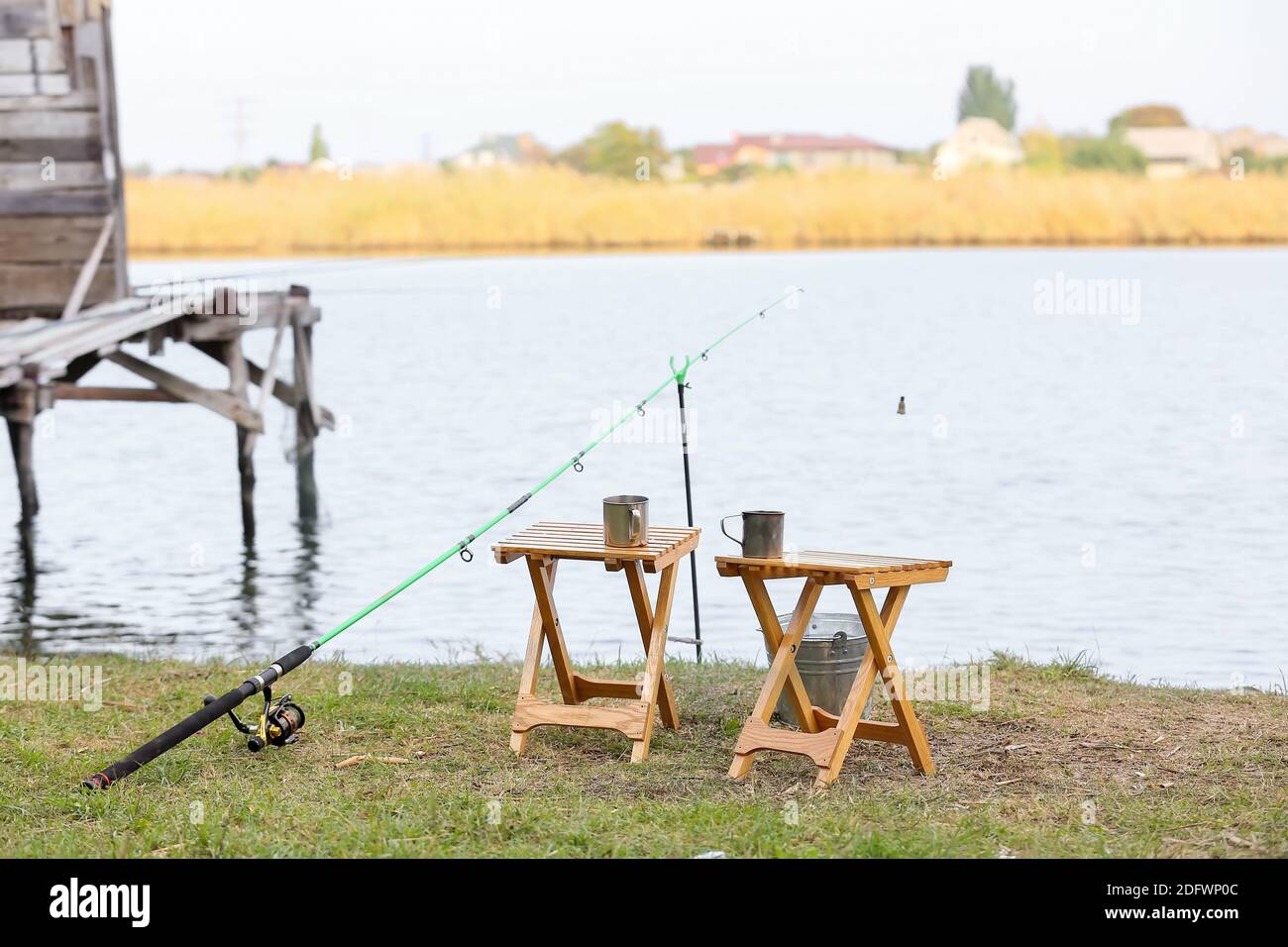Fishing rod, bucket and stools on river bank Stock Photo - Alamy