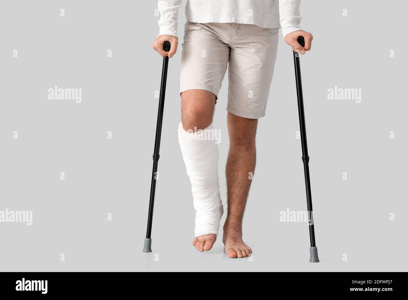 Young man with broken leg on grey background Stock Photo - Alamy