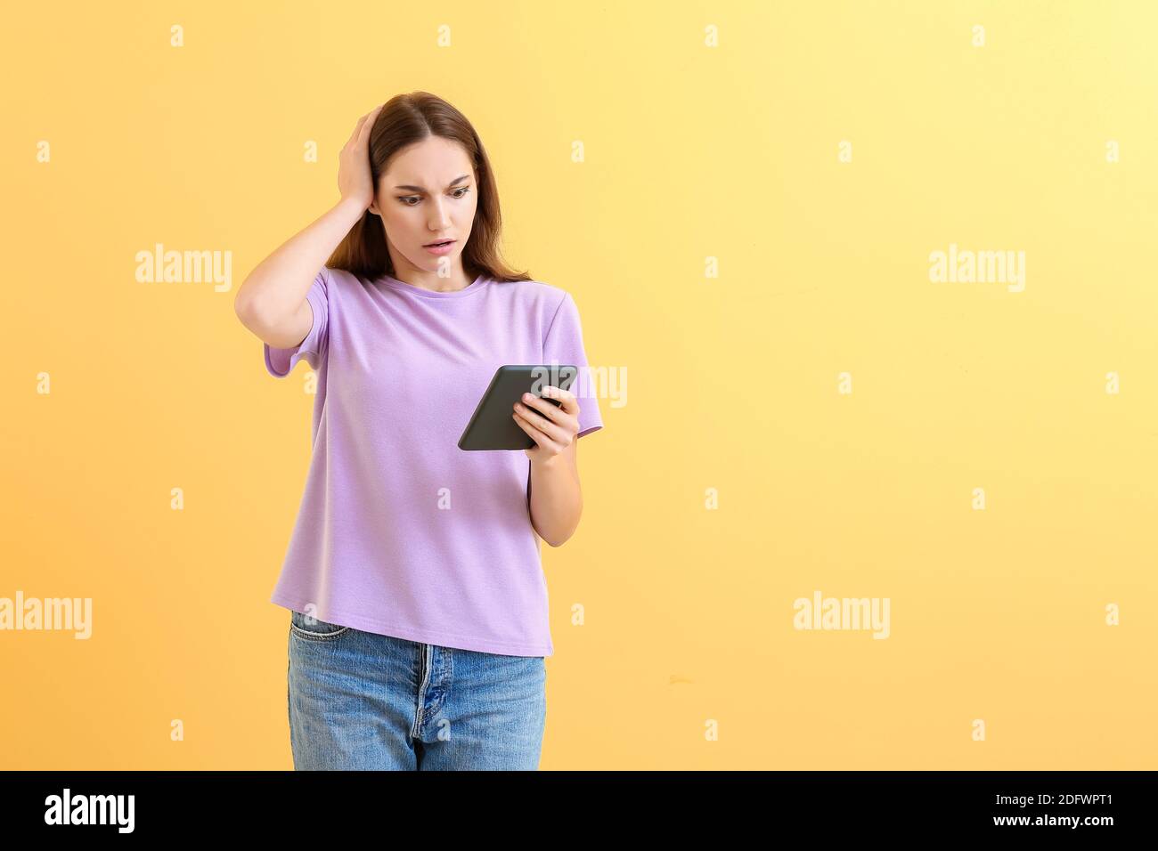 Shocked young woman with e-reader on color background Stock Photo - Alamy