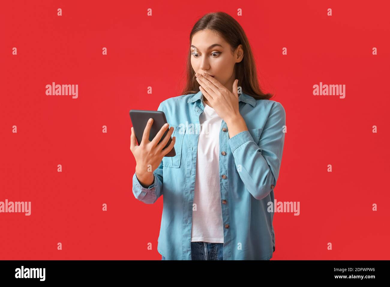 Shocked young woman with e-reader on color background Stock Photo - Alamy