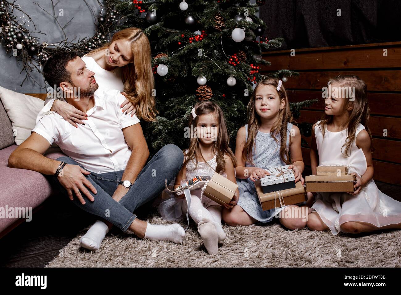 Happy cute family with three children exchanging gifts under the ...