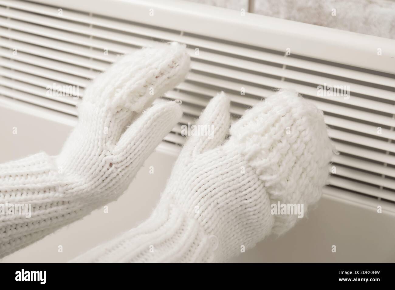 Woman warming hands at radiator. Concept of heating season Stock Photo ...