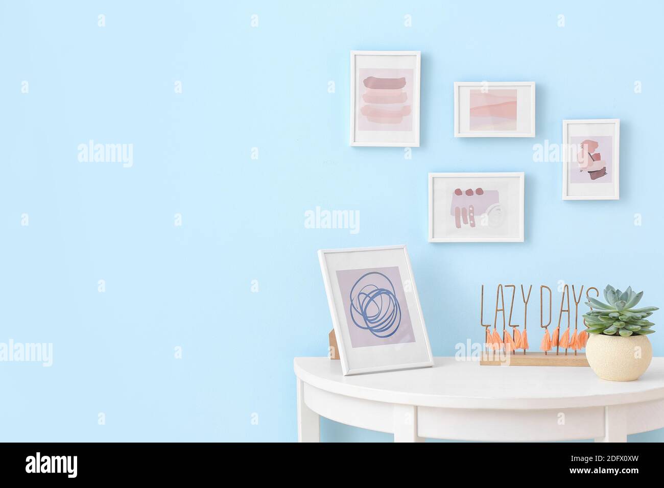 Table near wall with beautiful pictures Stock Photo - Alamy