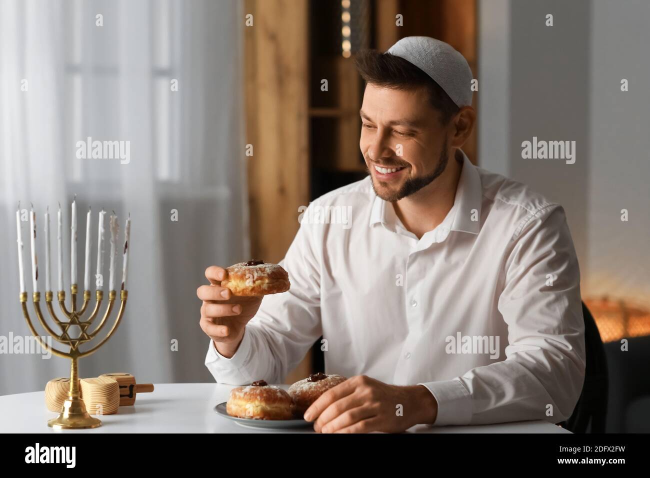 Man eating tasty donuts on Hannukah at home Stock Photo - Alamy