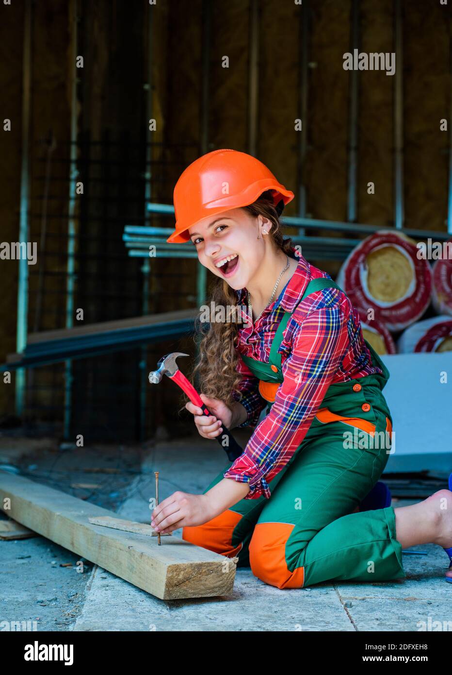 cheerful child laborer using building uniform and hammer tool, working ...