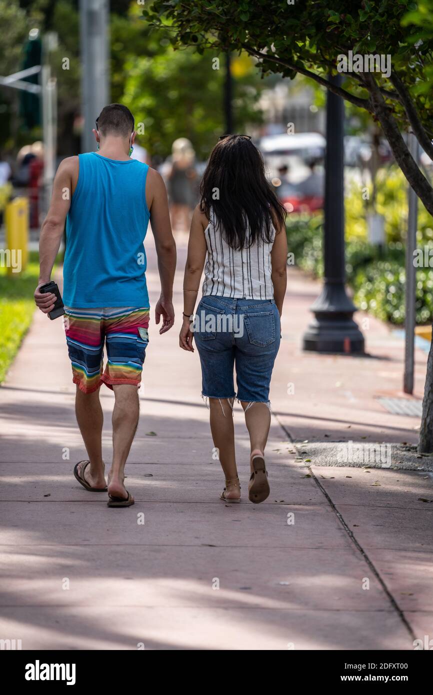 Street photography young couple walking away Miami Beach sidewalk Stock ...