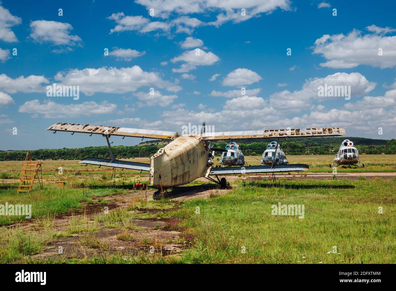 Abandoned, destroyed, rusty old planes stand on the grass under a blue ...
