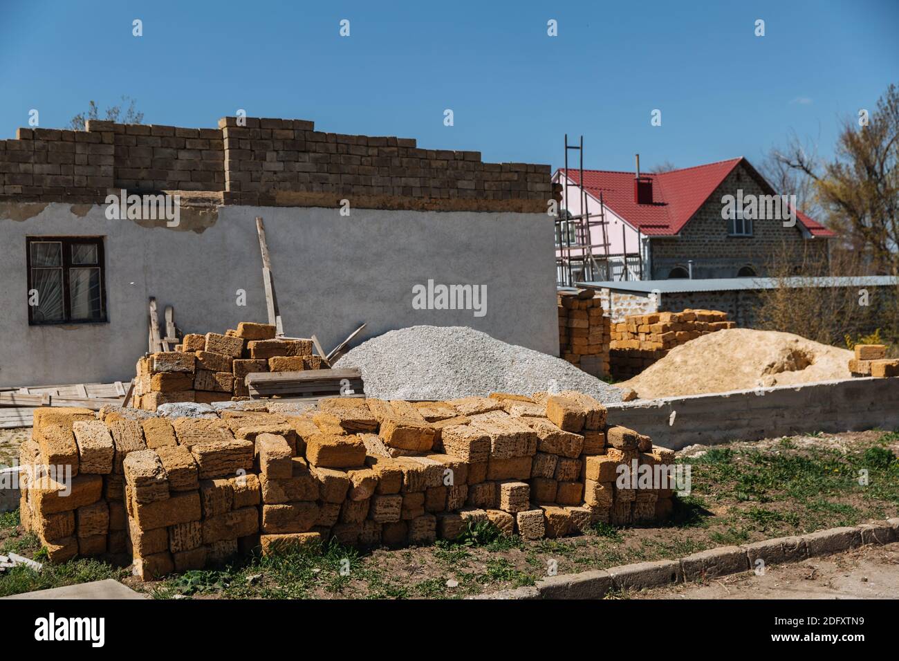 A pile of bricks lies in front of the house that is being built Stock ...