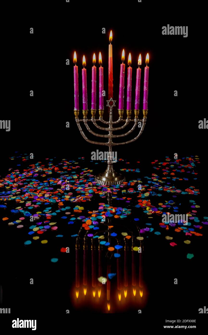 Burning menorah with pink candles and confetti on black background ...