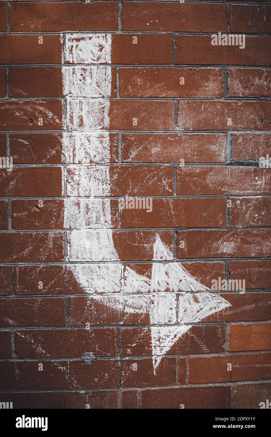 white turn arrow painted on a brick wall Stock Photo - Alamy