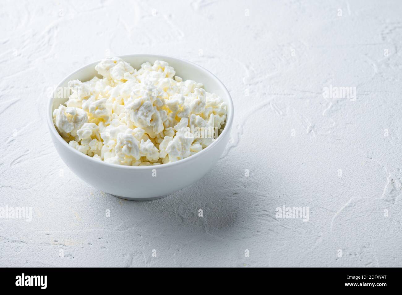 Cottage cheese, curd, on white textured background with space for text ...