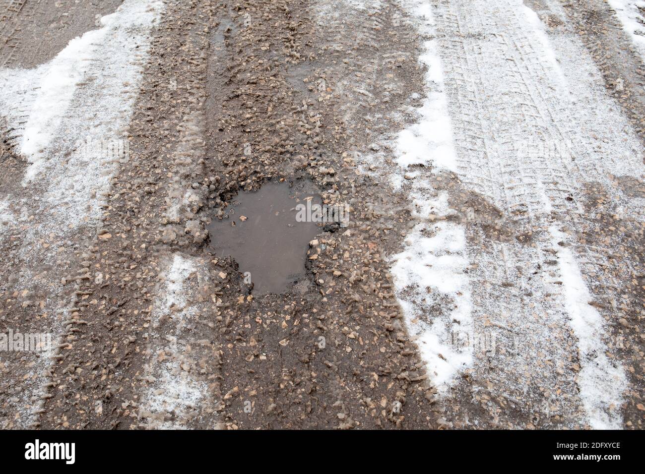 Road with pits, snow and puddles. Winter, weather, ice and danger Stock ...