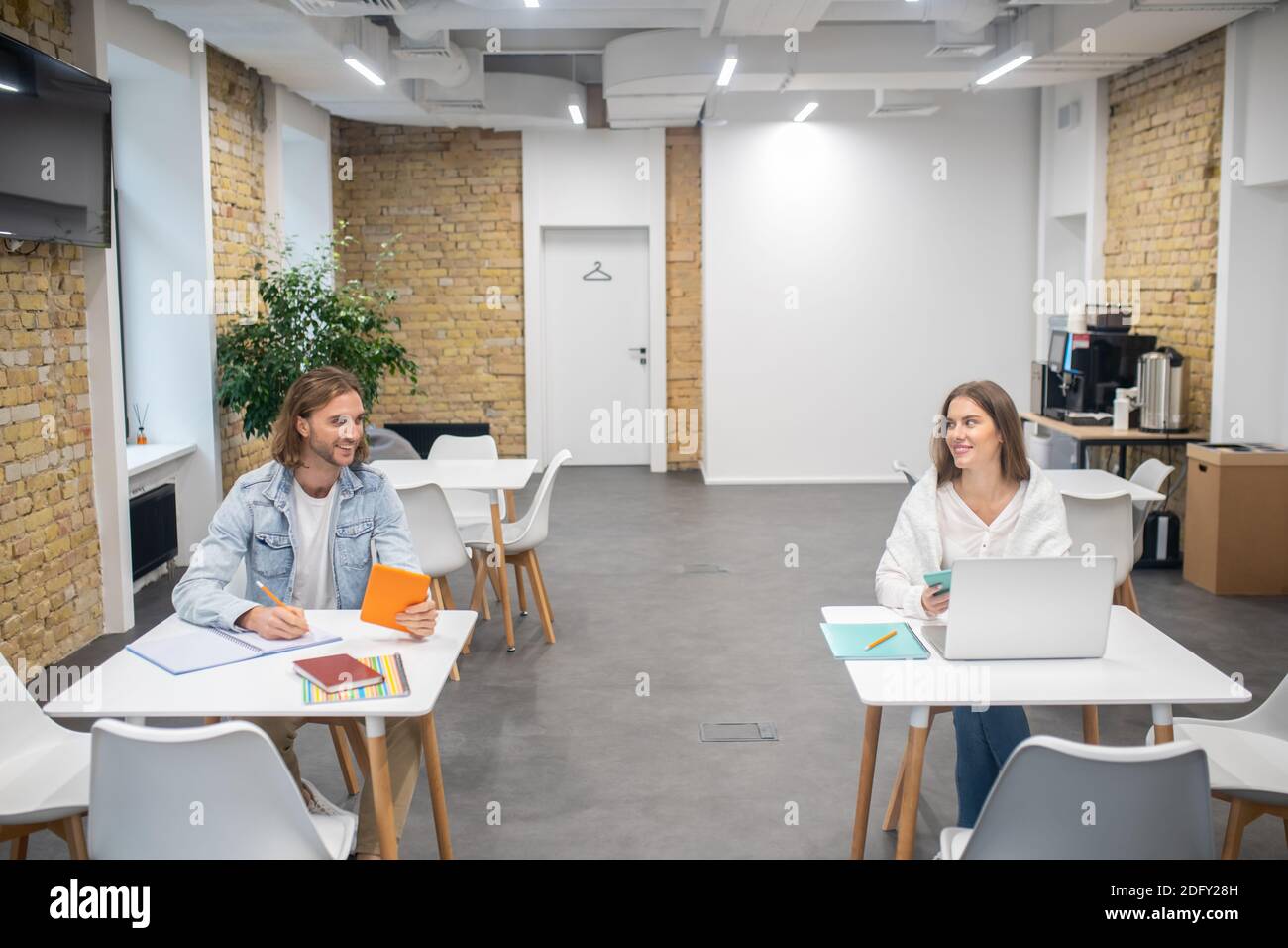 Two colleagues sitting at the tables working in the office Stock Photo ...