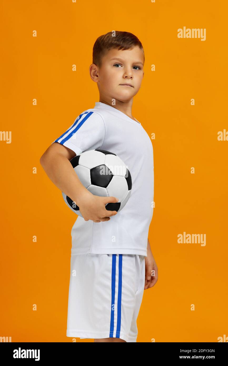 little boy football player in uniform holding ball over yellow ...