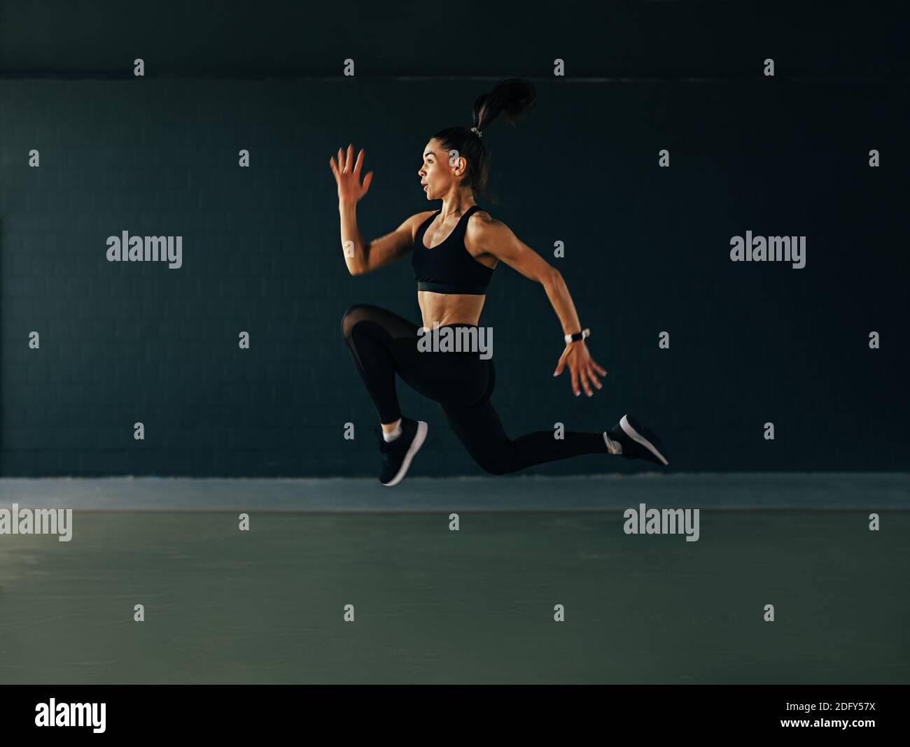Side view of a woman jumping indoors. Female doing an intense workout ...