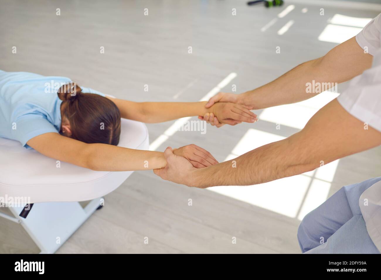 Hands of man chiropractor pulling lyong woman patients hands to fix her ...