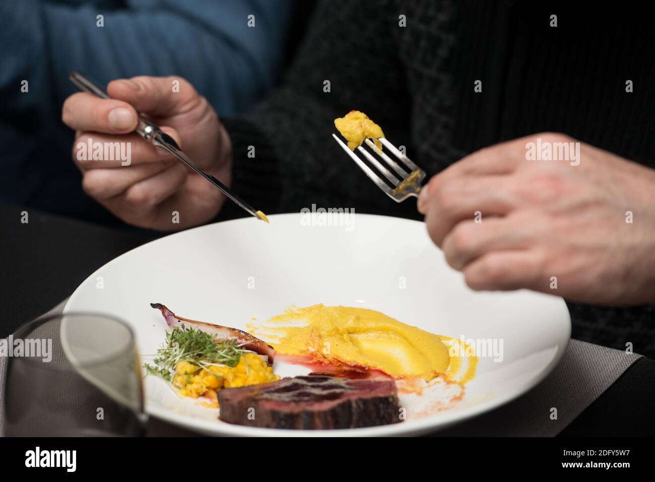 Men in a restaurant eating medium grilled cut pork steak with blood on ...