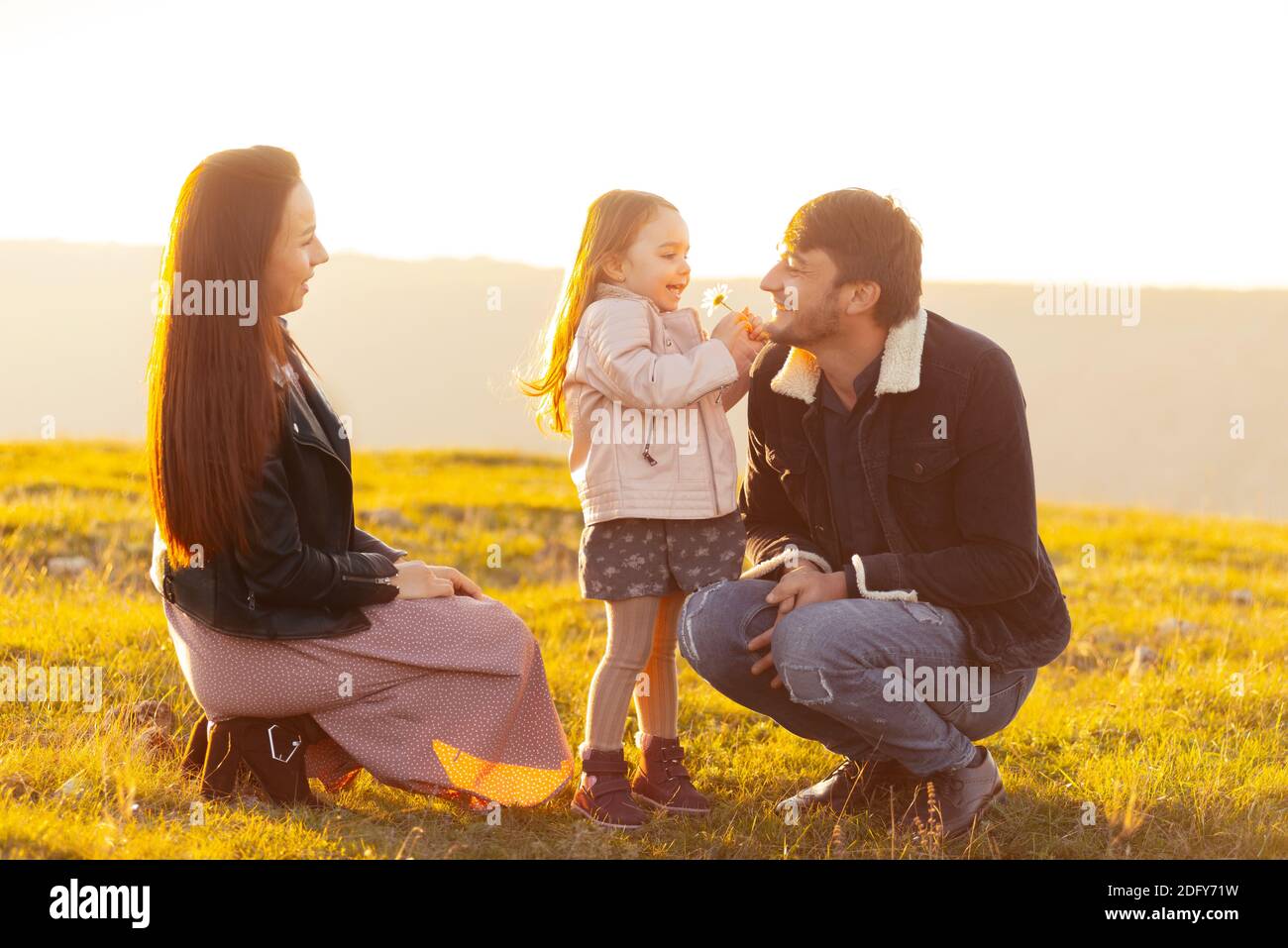 Mom dad and daughter having time together on nature, in filed on sunset ...
