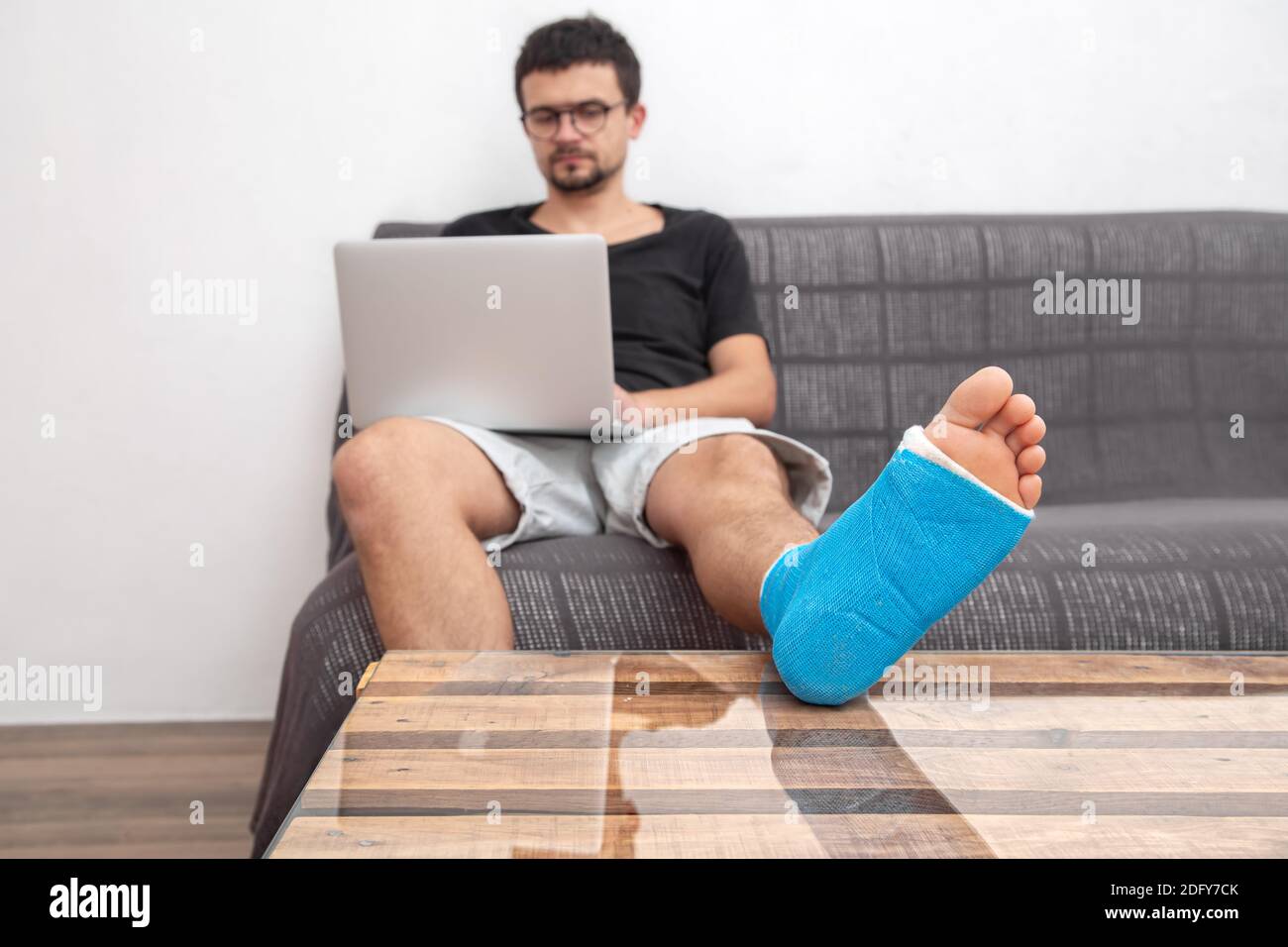 Man with glasses with broken leg in blue splint for treatment of ...