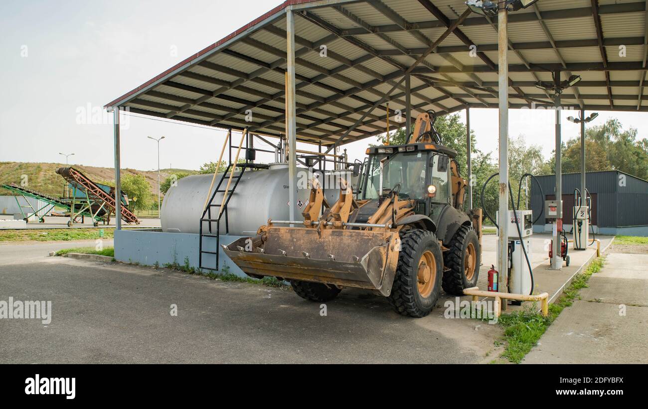 Yellow tractor on gas station. Refill. Heavy equipment. Tanks with fuel ...