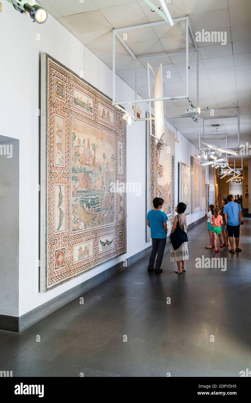 People looking at Roman period wall mounted mosaics in a corridor of ...