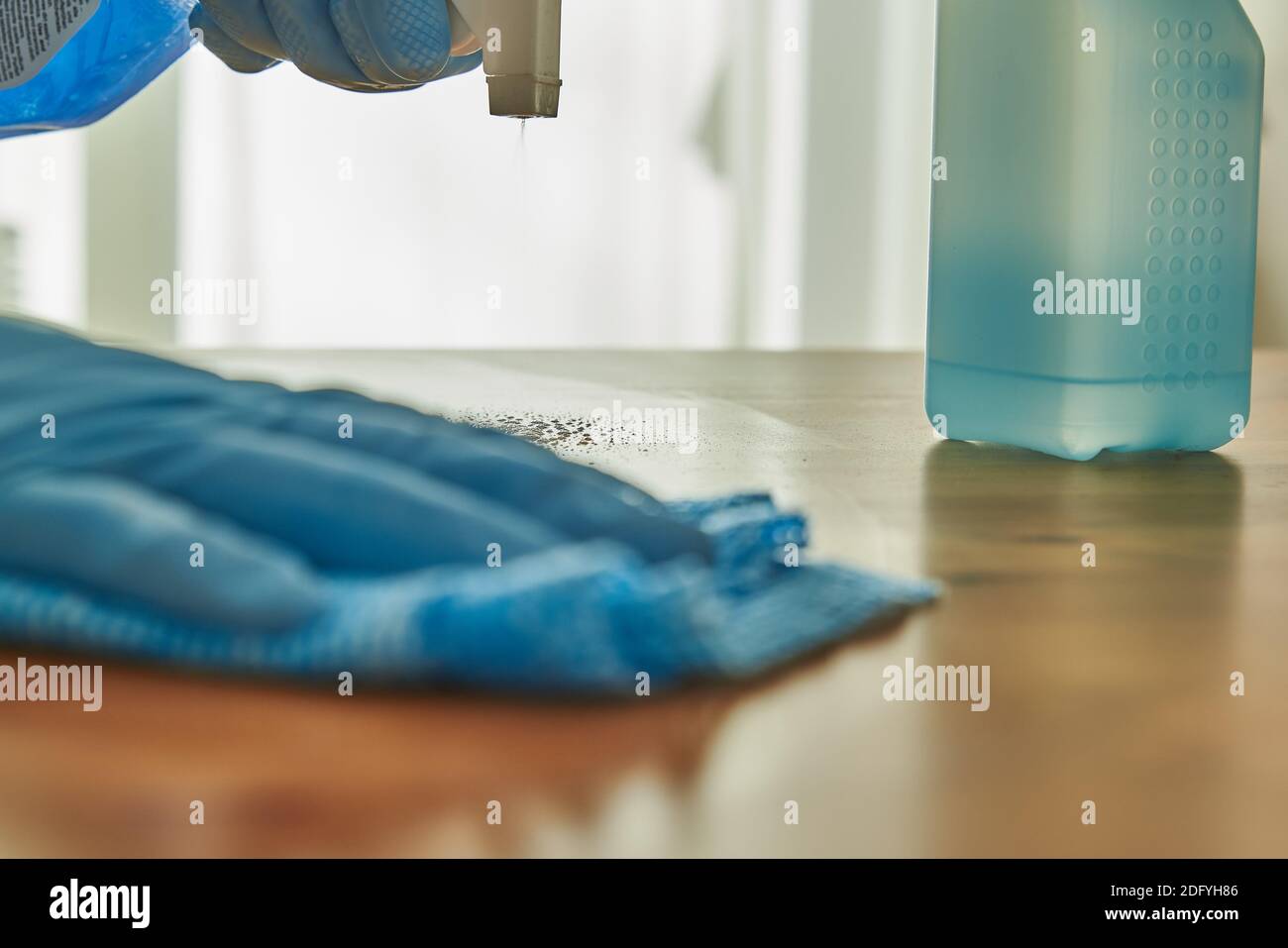 Person disinfecting a table with disinfectant. Cleaning a surface with ...