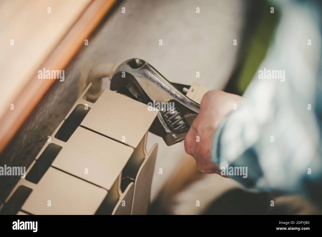 Repairman working on radiator with wrench Stock Photo - Alamy