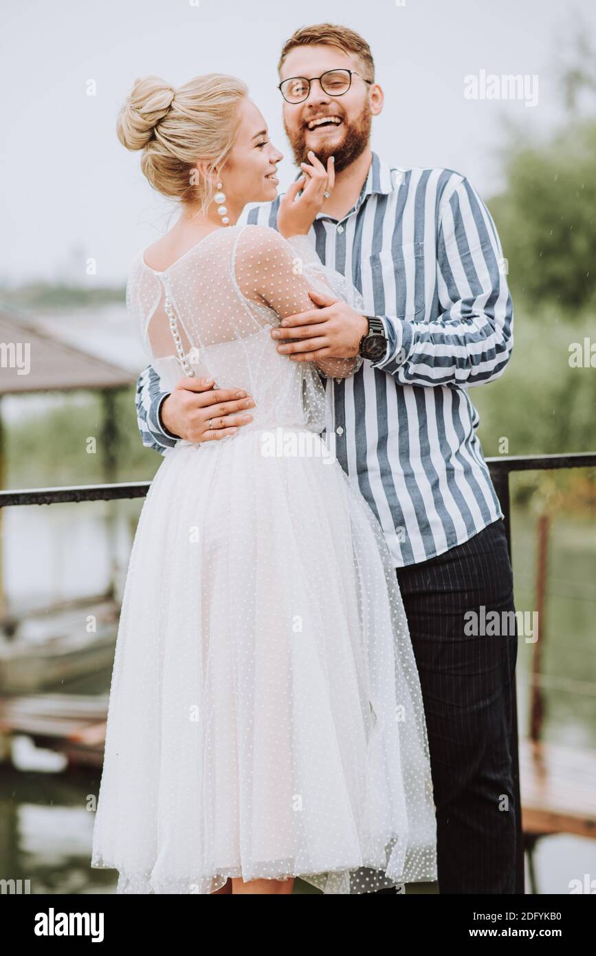 The bride and groom tenderly hugging they stand and pose on the pier ...