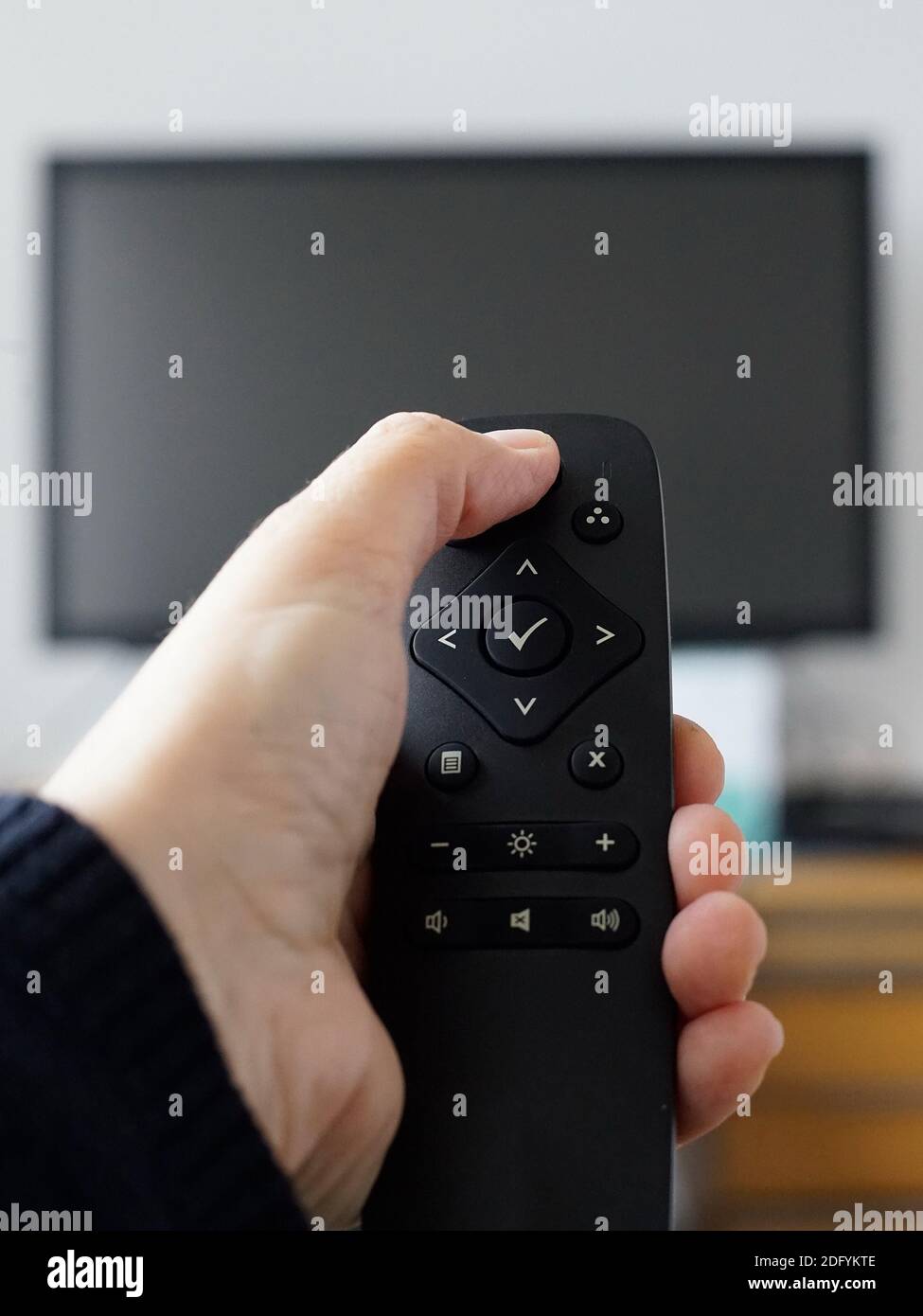 A hand holding a remote control for turning the TV on han Stock Photo ...