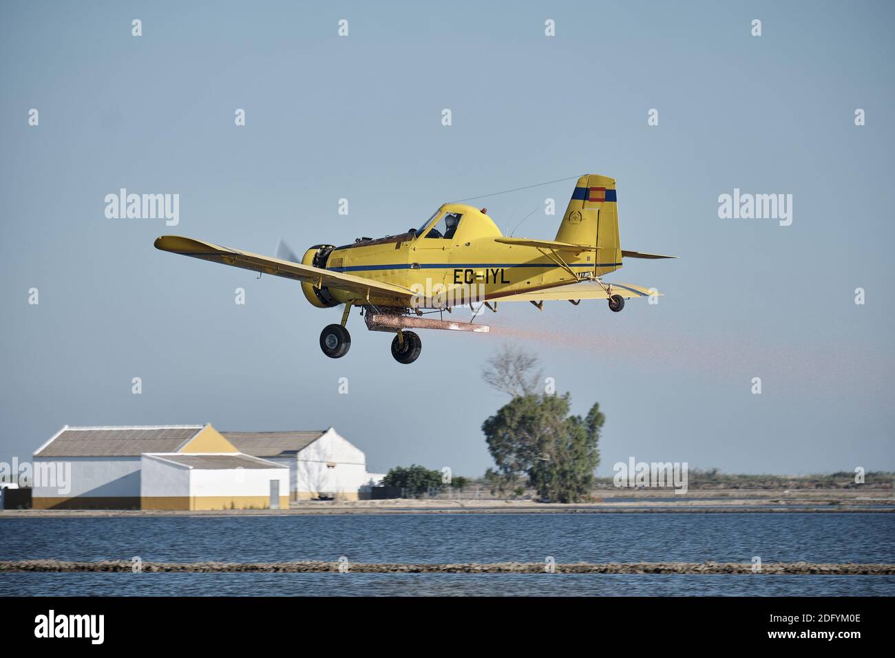 A vintage single-engine aircraft with a propeller flying over a farm ...