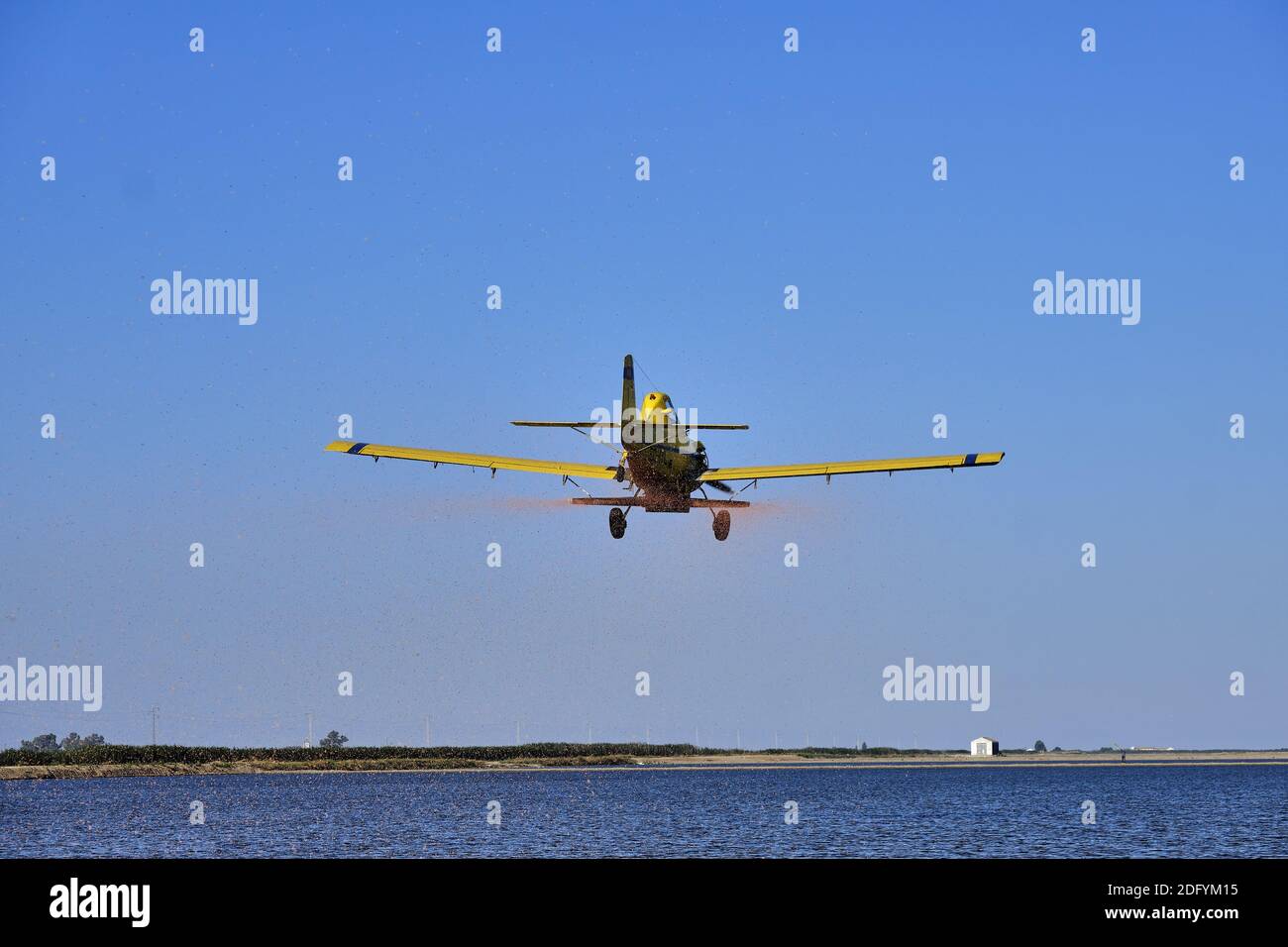 A vintage single-engine aircraft with a propeller flying over a farm ...