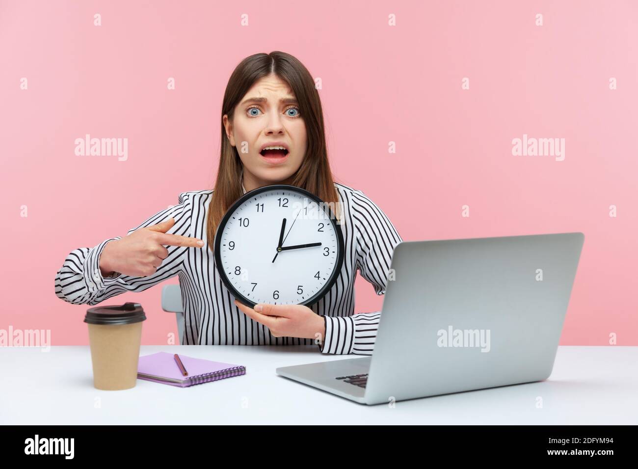 Nervous anxious woman office worker pointing finger at big wall clock ...