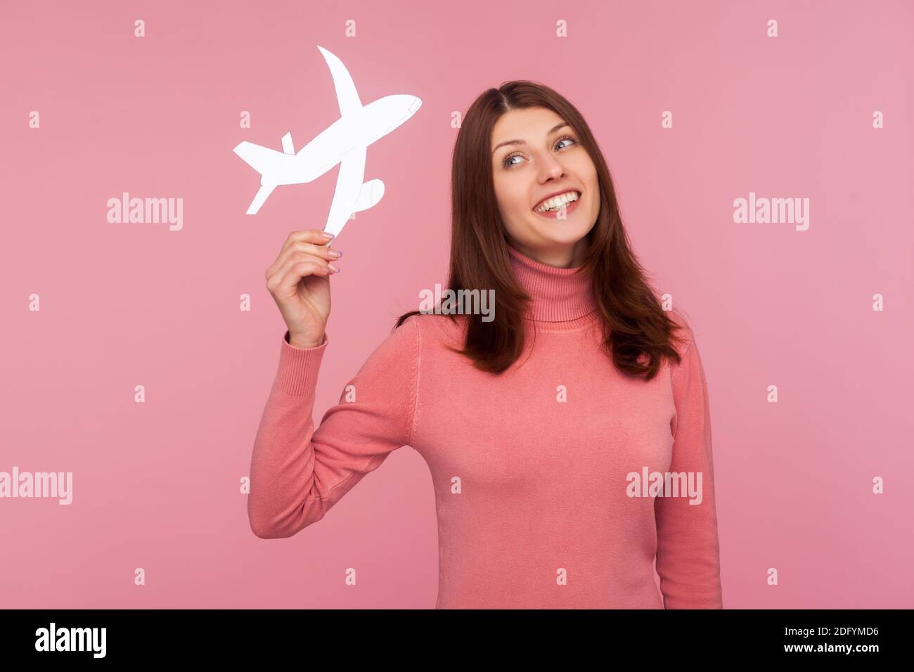Cheerful positive brunette woman holding in hand paper plane looking ...