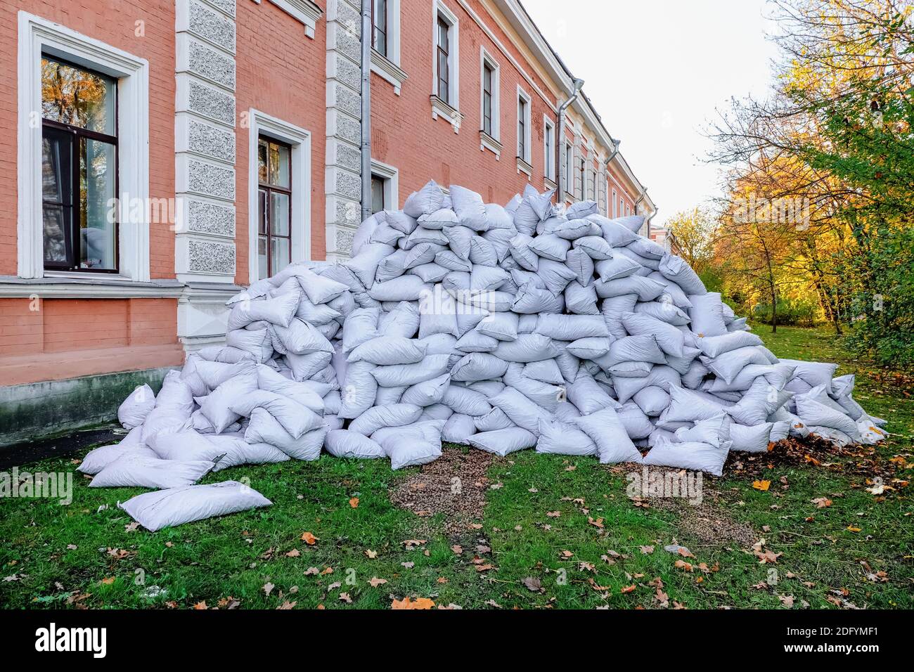 A pile of filled construction bags lie in front of the building. A pile ...