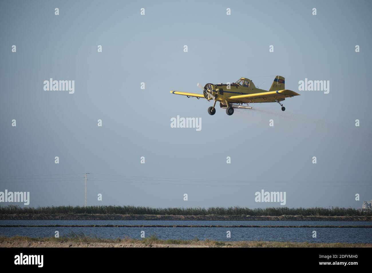 A vintage single-engine aircraft with a propeller flying over a farm ...