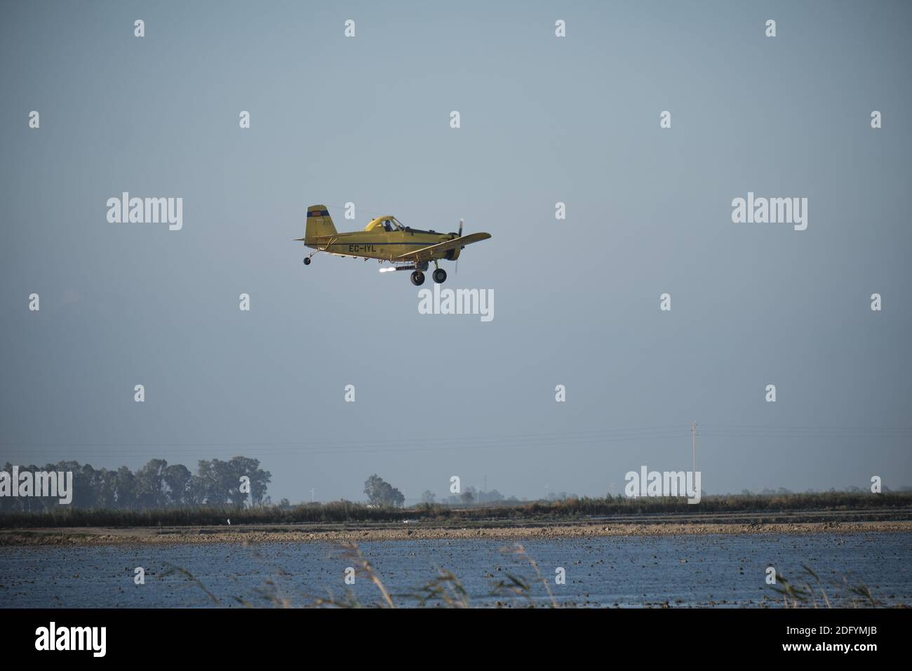 A vintage single-engine aircraft with a propeller flying over a farm ...