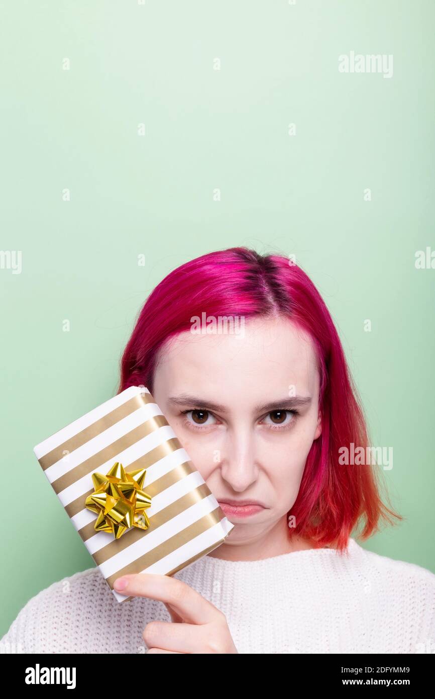 Woman in white sweater with gift box in hand is unhappy with gift and ...