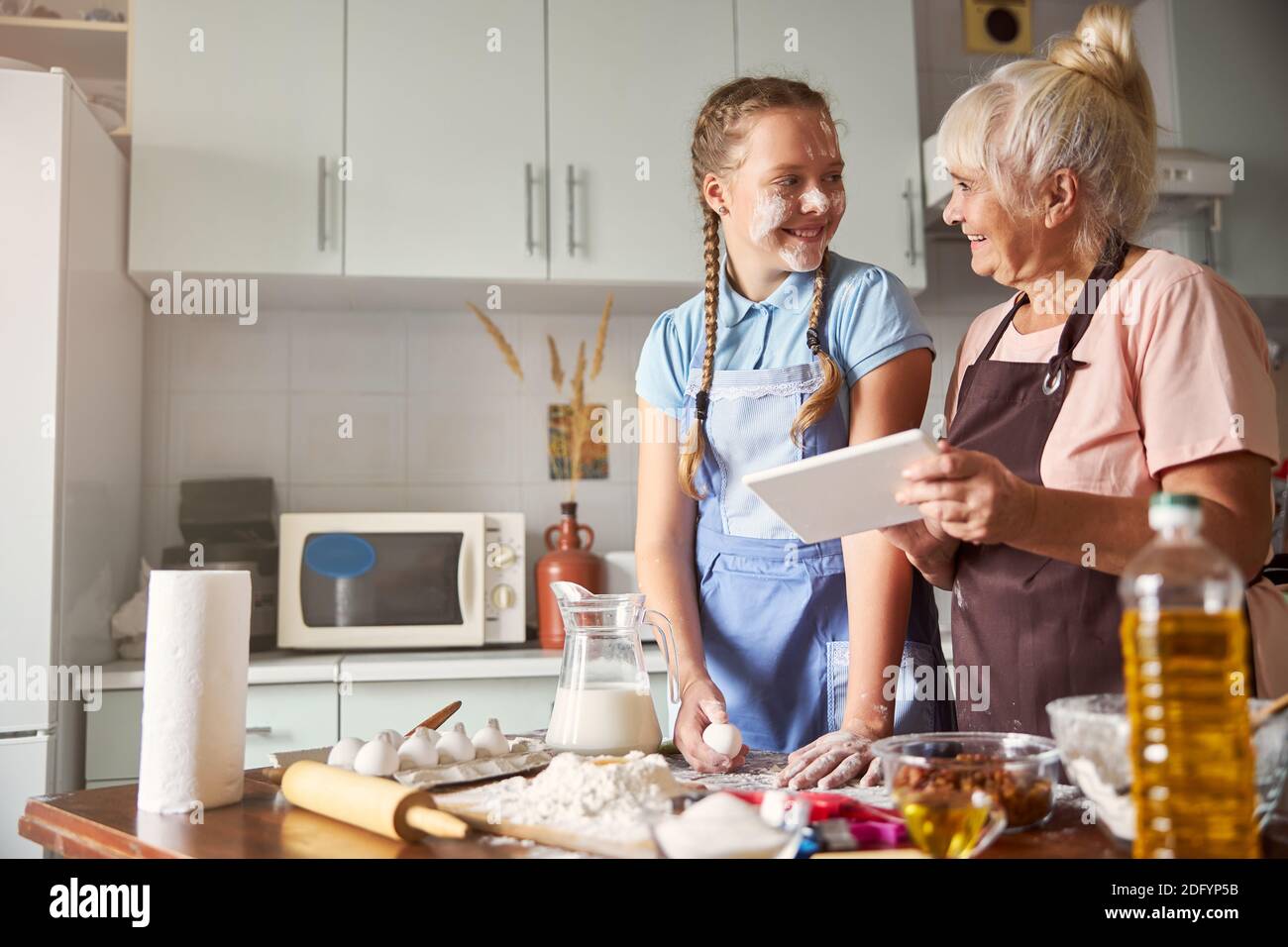 Grandma sharing her baking knowledge with jolly granddaughter Stock ...